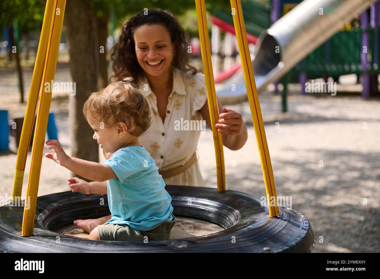 A joyful scene of a mother and child playing on a tire swing at the ...