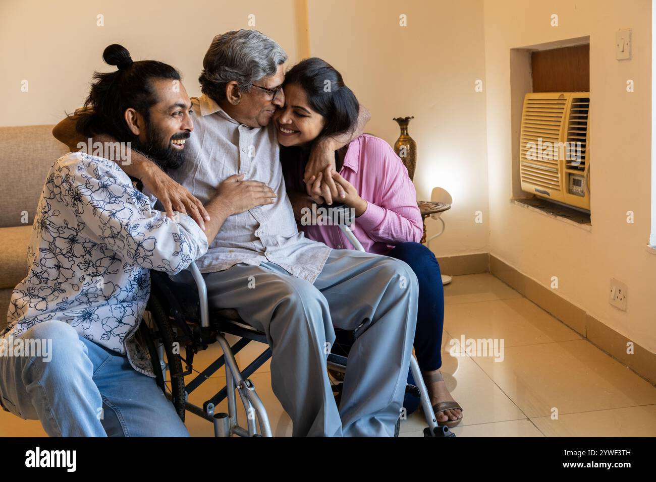 Happy Indian young couple spending time with disabled father on wheel ...