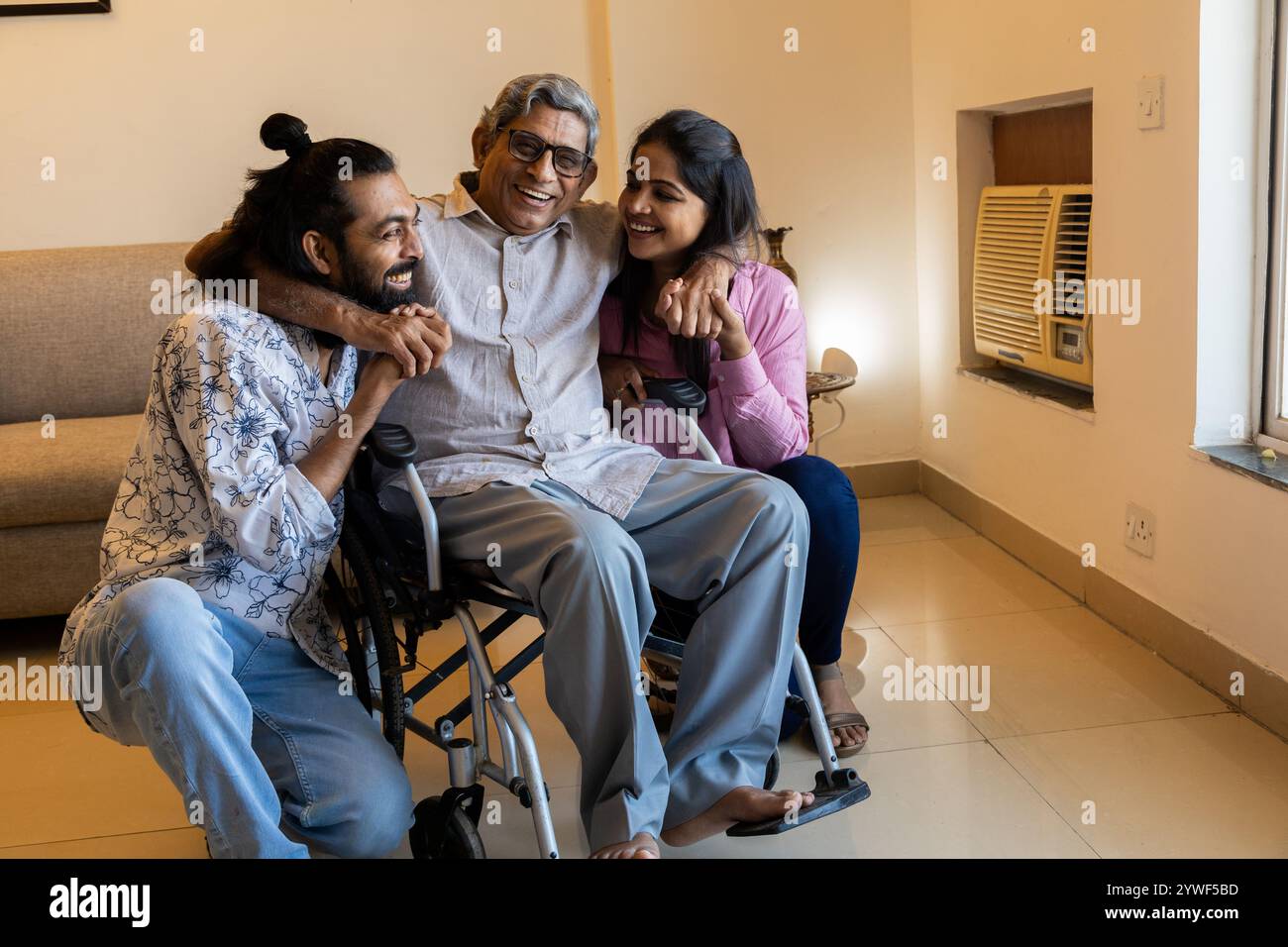 Happy Indian young couple spending time with senior disabled father on ...