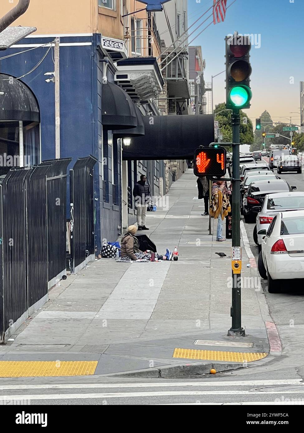 A homeless person sits silently on the ground, surrounded by their few ...