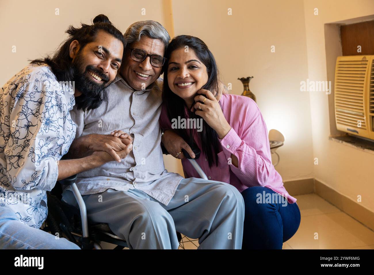 Happy Indian young couple spending quality time with disabled father on ...
