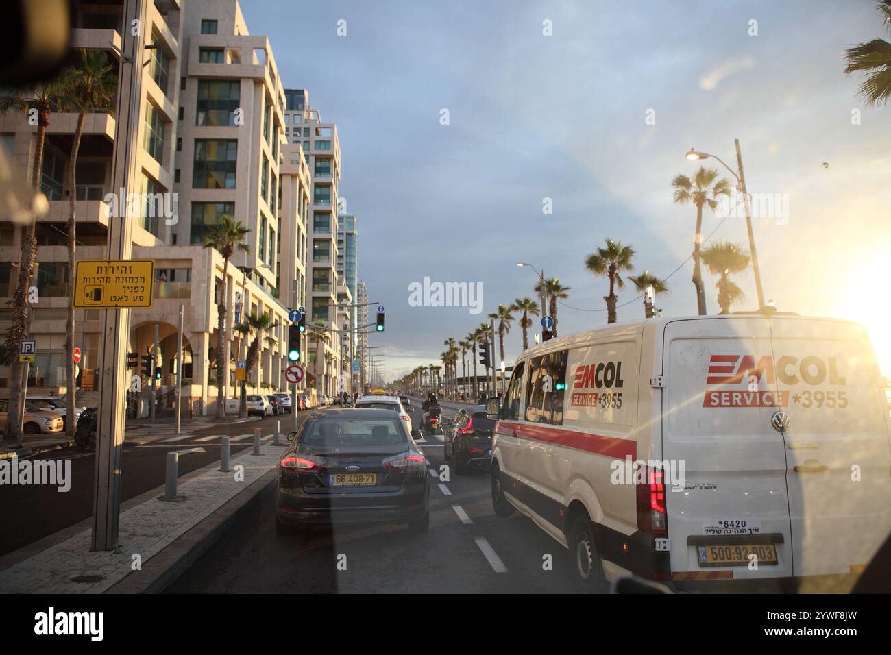 Tel Aviv traffic at sunset. Herbert Samuel St. seen through a car front windshield, tall ...