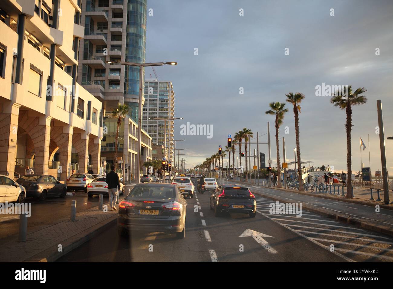 Tel Aviv traffic at sunset. Herbert Samuel St. seen through a car front windshield, tall ...