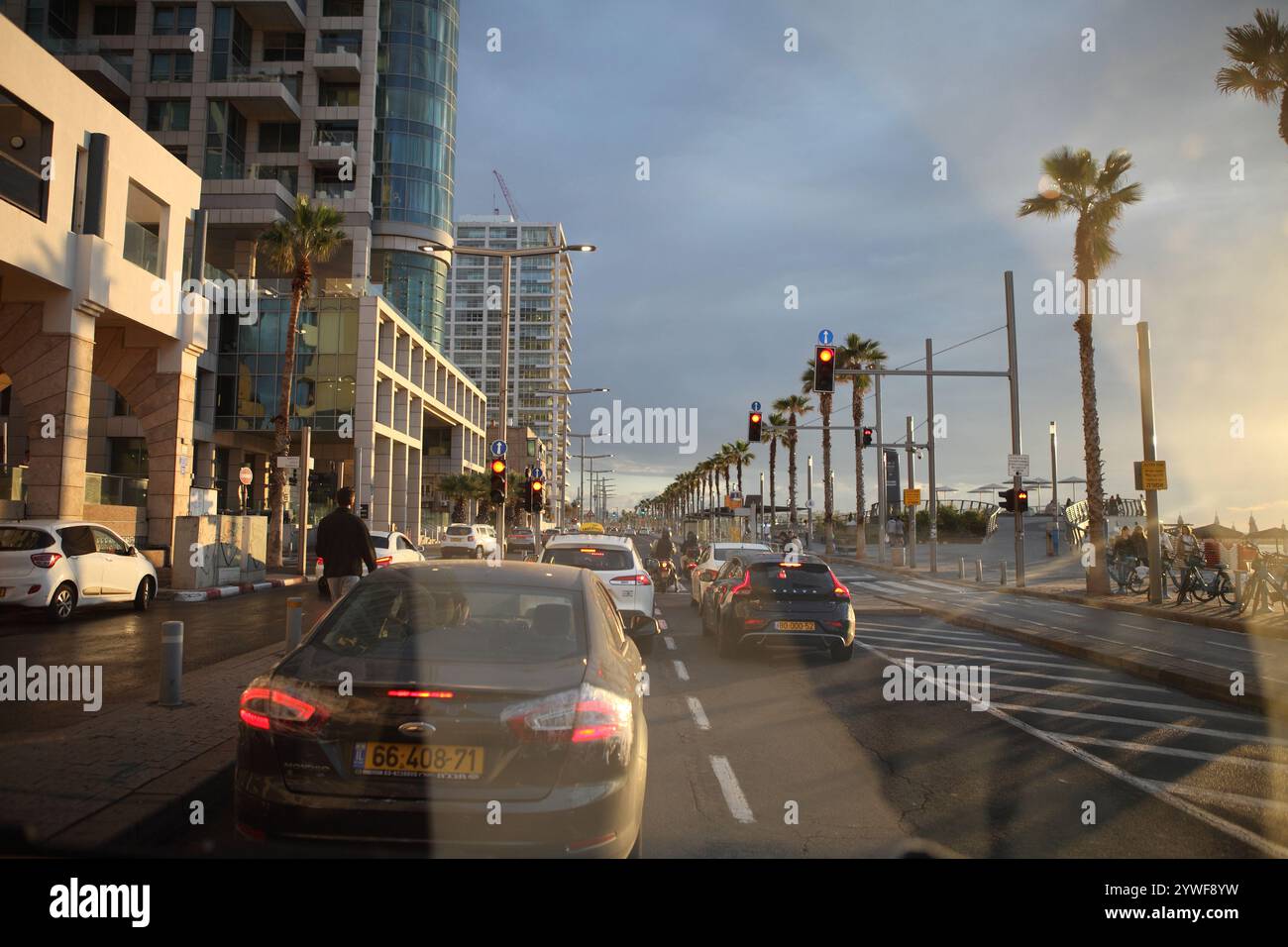 Tel Aviv traffic at sunset. Herbert Samuel St. seen through a car front windshield, tall ...