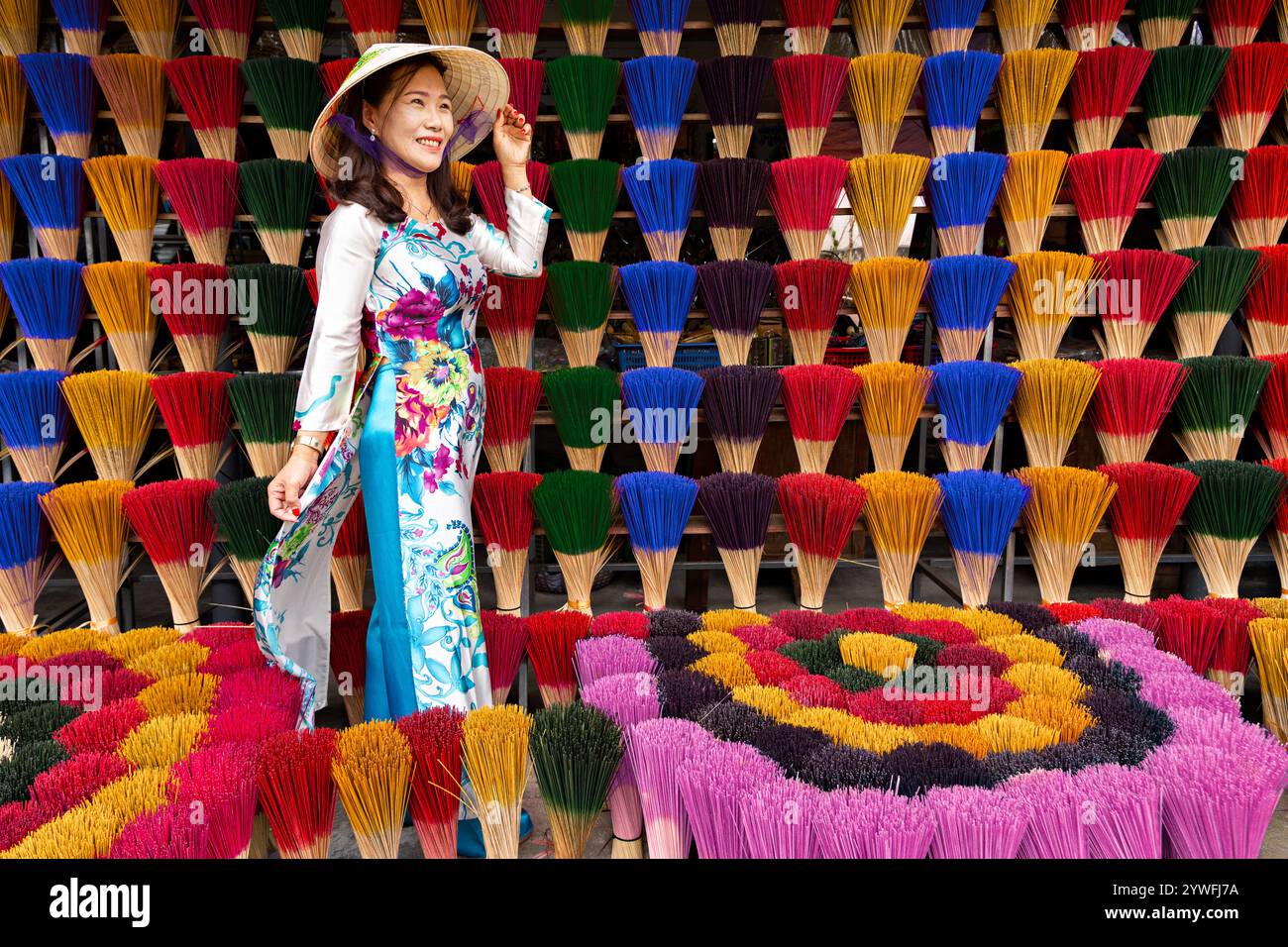 Local woman in traditional costume amongst the incense sticks in Hue ...