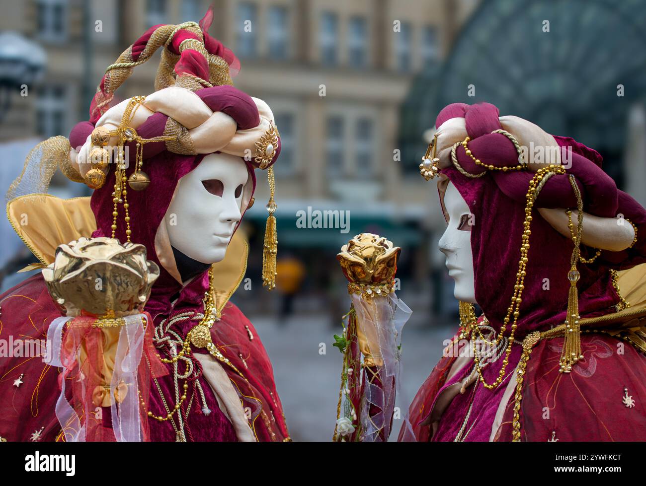 Elegant masked figures in ornate costumes at a cultural festival in a ...
