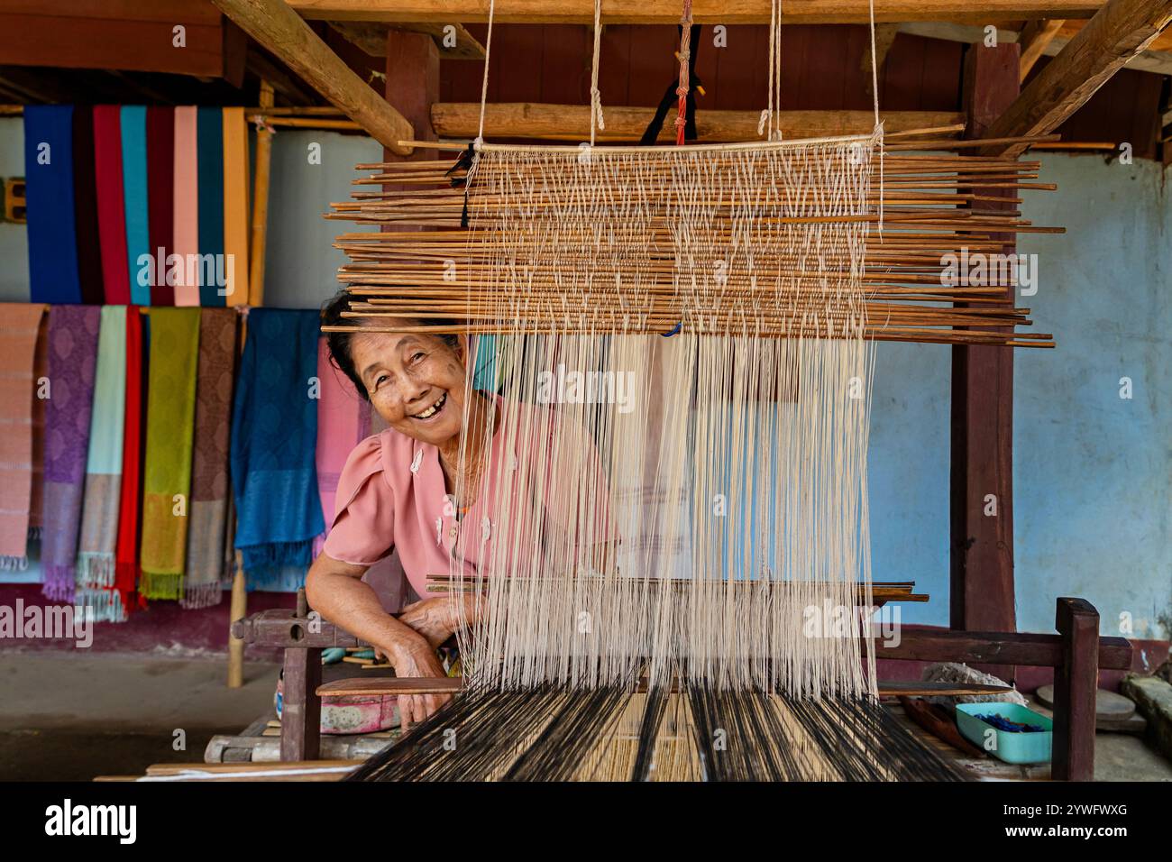 Elderly woman weaving and looking through the threads of the loom in ...