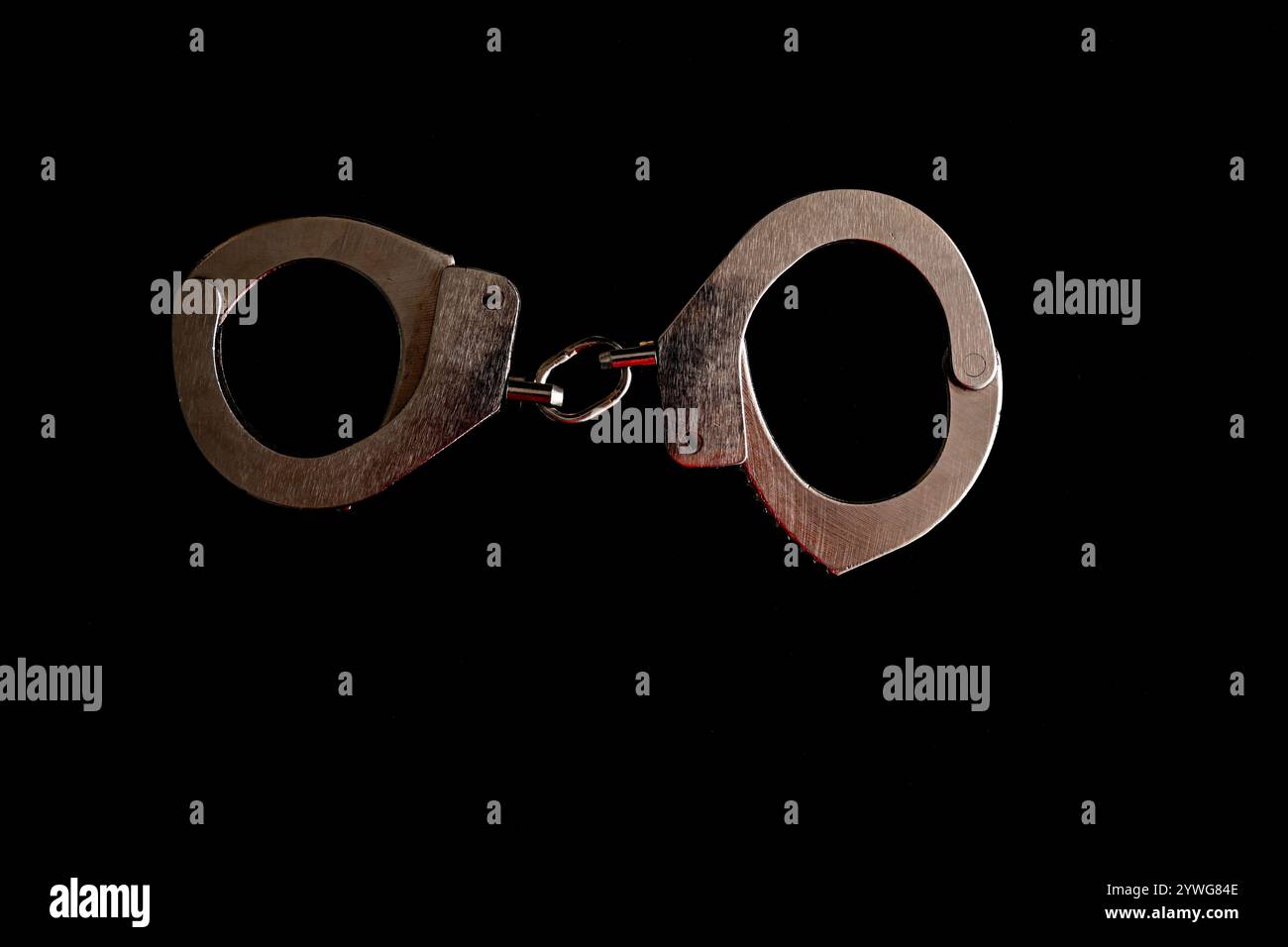 Steel handcuffs lying on a dark background, representing concepts of ...