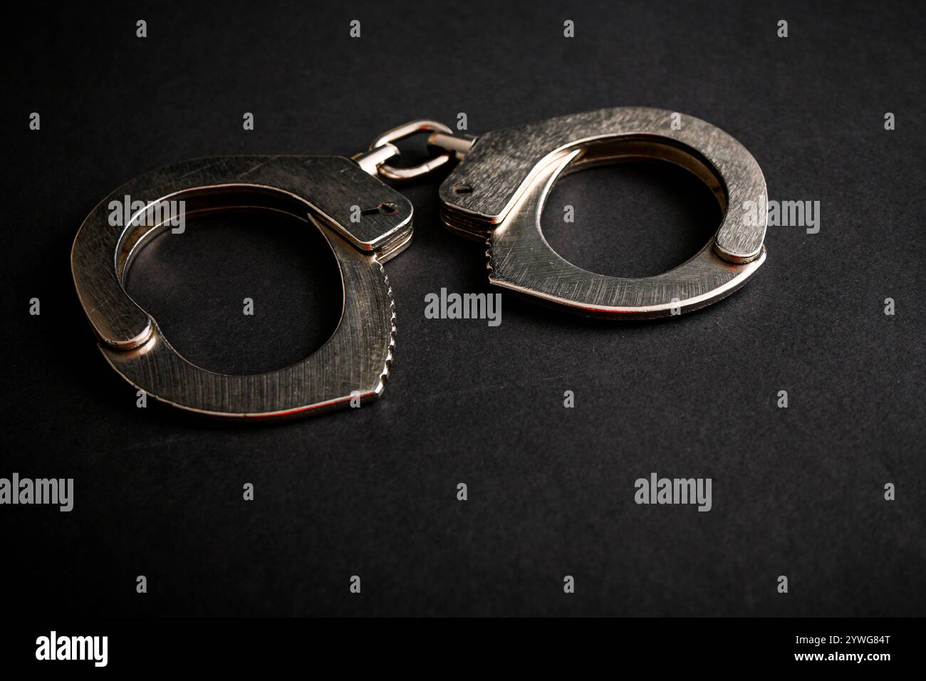 Steel handcuffs lying on a dark background, representing concepts of ...