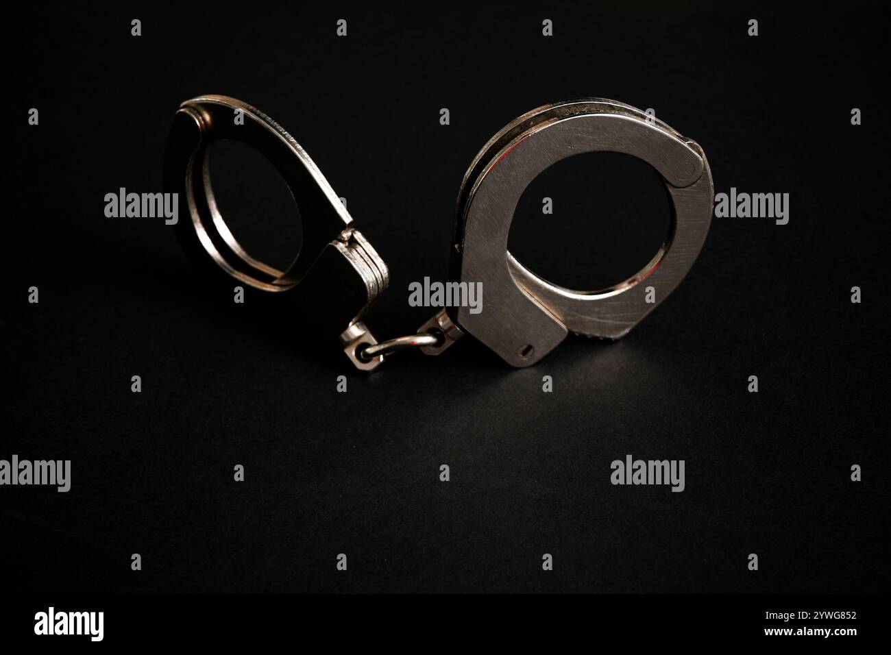 Steel handcuffs lying on a dark background, representing concepts of ...
