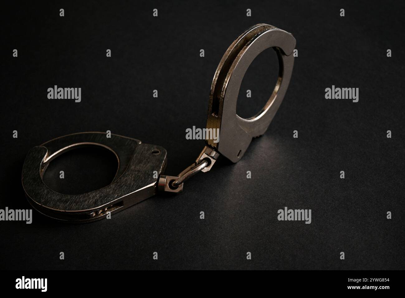 Steel handcuffs lying on a dark background, representing concepts of ...