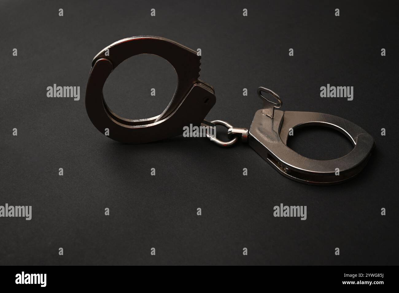Steel handcuffs lying on a dark background, representing concepts of ...