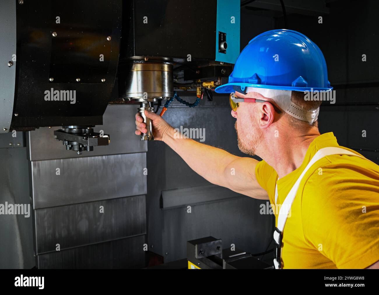 Metalworker is changing the drill bit in a cnc machine during a metal ...