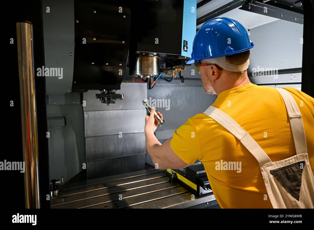 Metalworker is changing the drill bit in a cnc machine during a metal ...