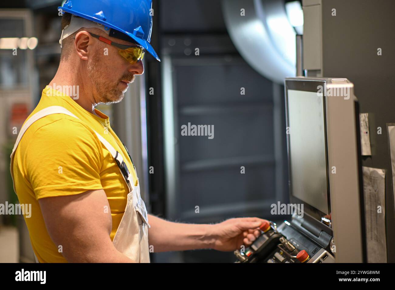 Metalworker wearing safety glasses and hardhat using cnc milling ...