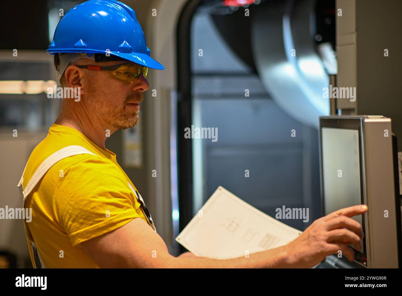 Industrial engineer managing a cnc milling machine using a computer ...