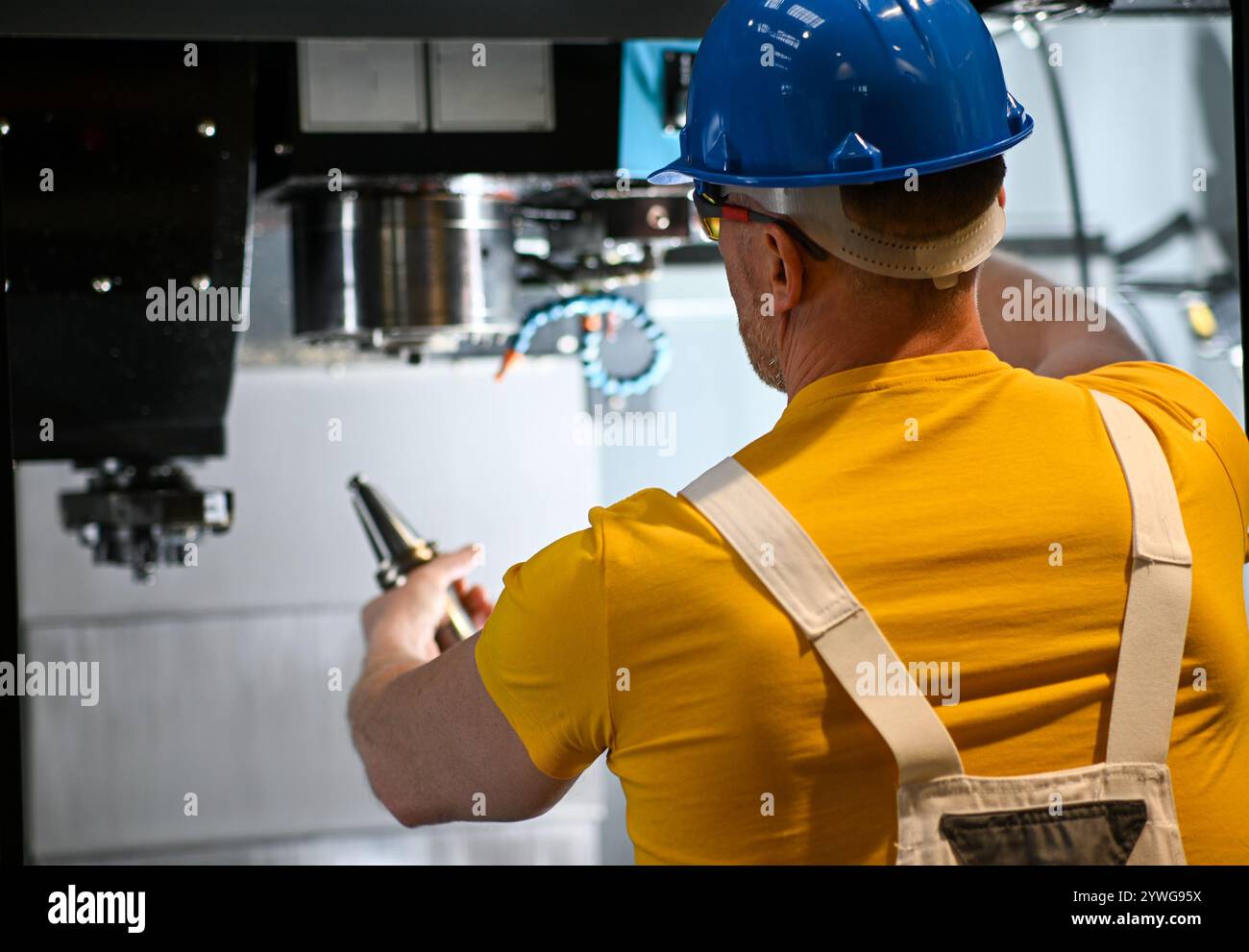 Metalworker is changing the drill bit in a cnc machine during a metal ...