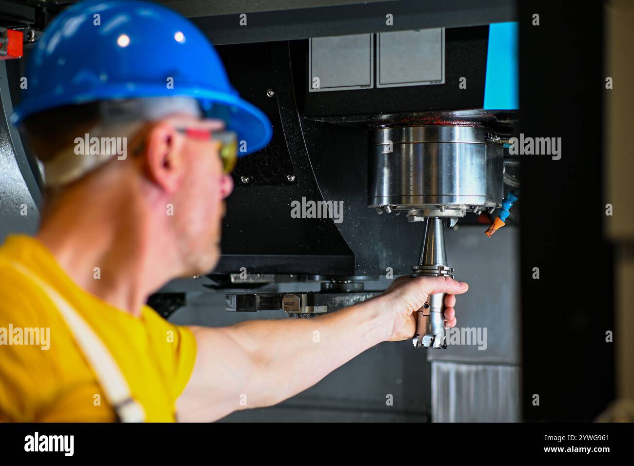 Metalworker is changing the drill bit in a cnc machine during a metal ...