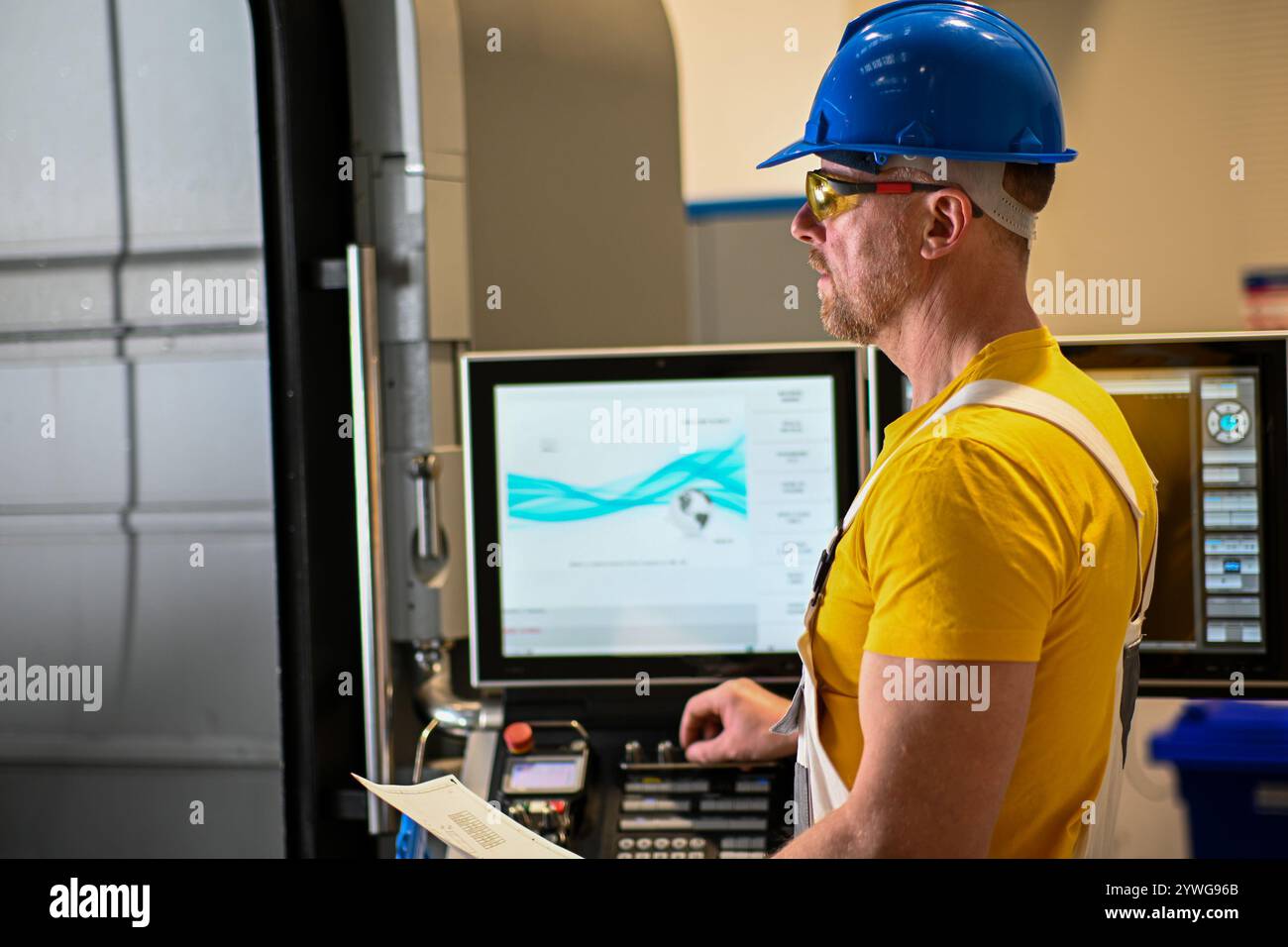Industrial engineer managing a cnc milling machine using a computer ...