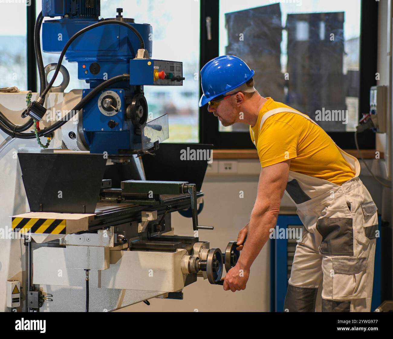 Factory worker operating a milling machine, demonstrating workplace ...
