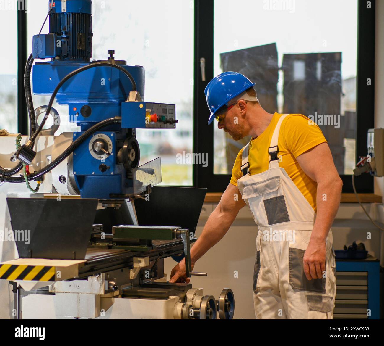 Factory worker operating a milling machine, demonstrating workplace ...