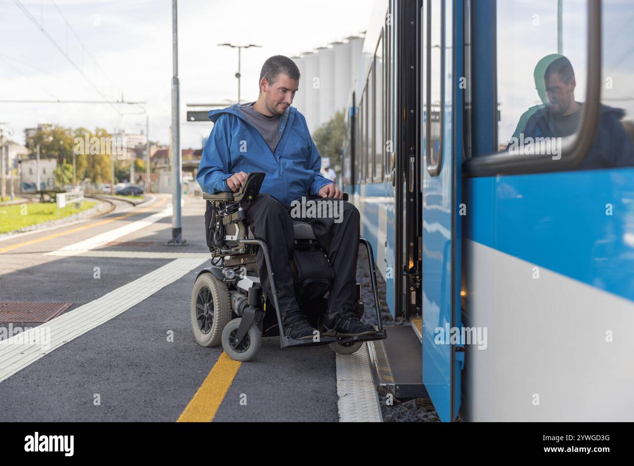 Man with disability, an electric wheelchair user entering a train ...