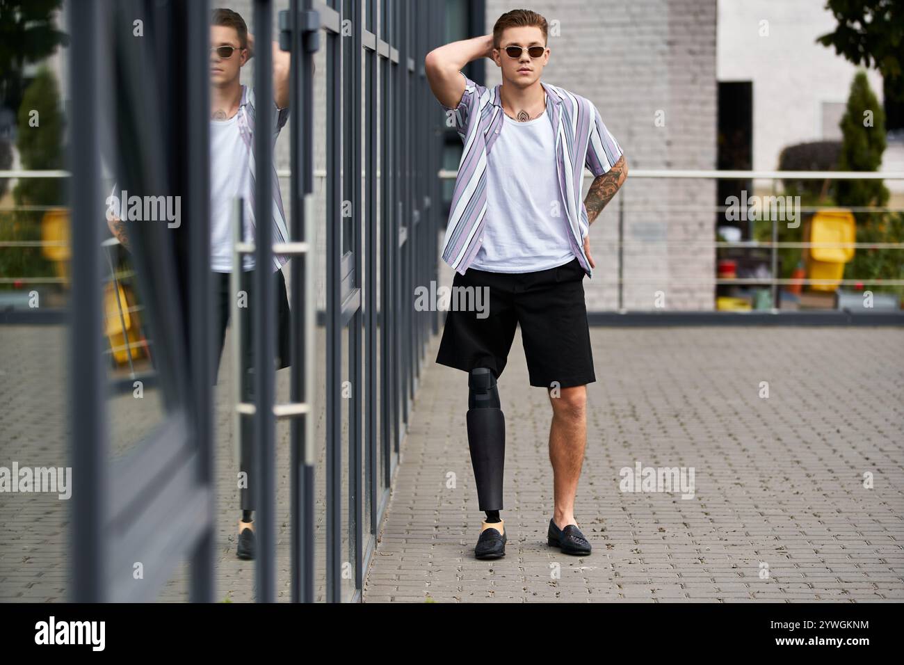 Handsome young man with a prosthetic leg poses confidently near modern ...