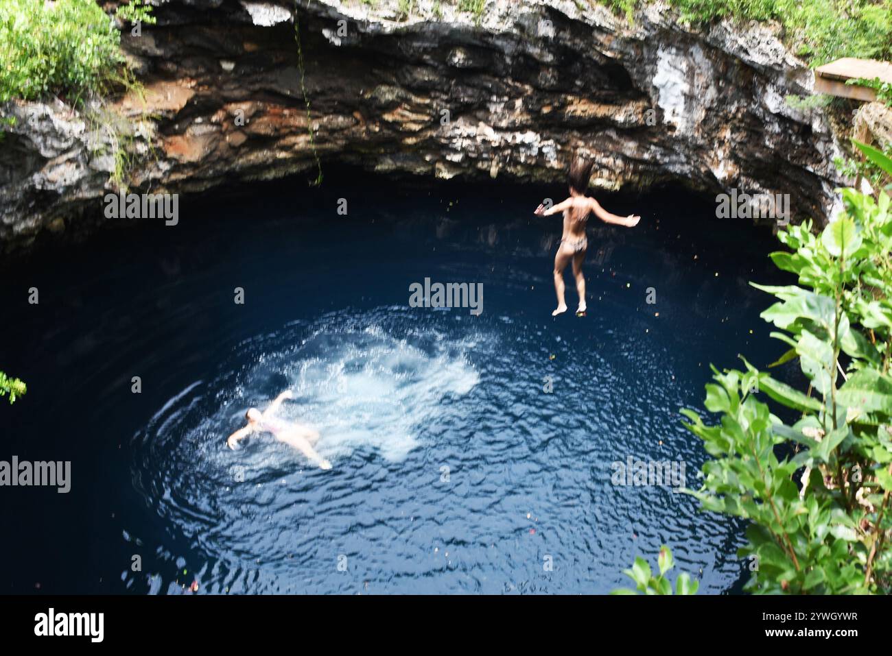 A woman joyfully leaps into the vibrant, deep blue waters of the ...
