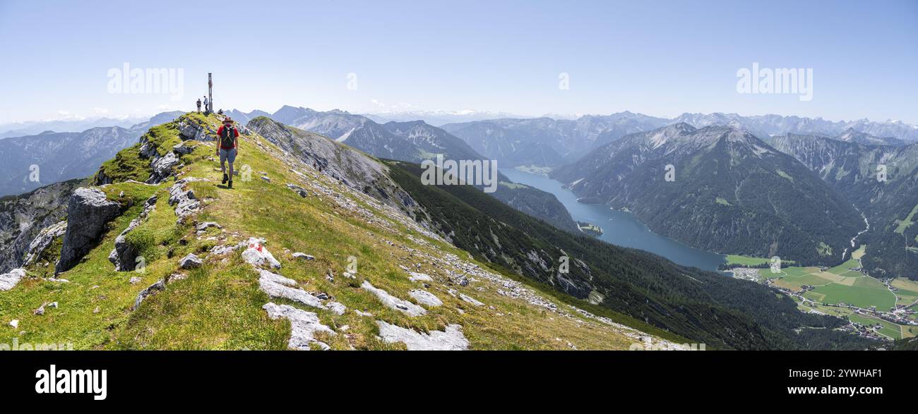 Mountaineer on the summit ridge of Hochunnuetz with summit cross ...