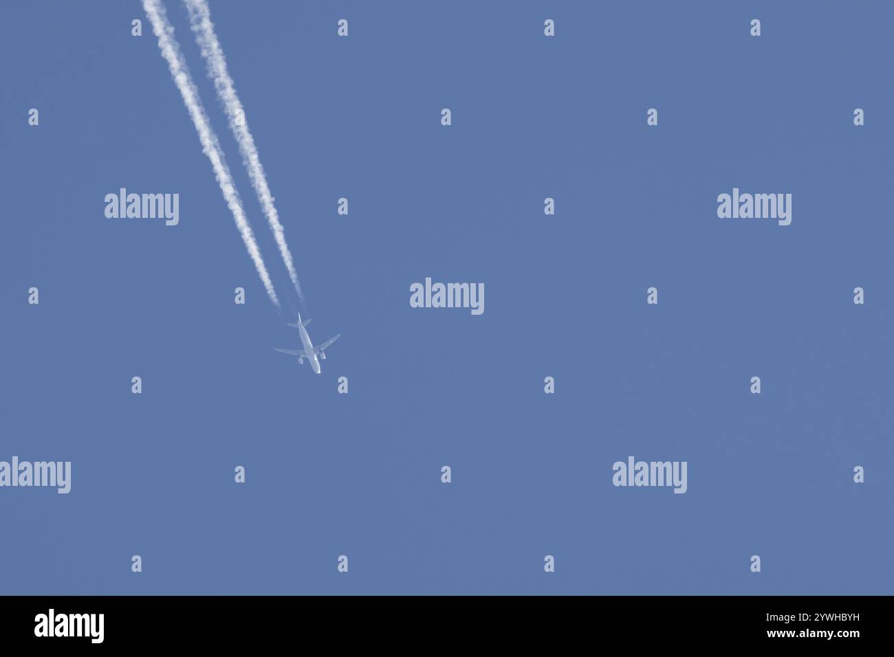 Airbus jet aircraft flying in a blue sky with a vapor trail or contrail ...