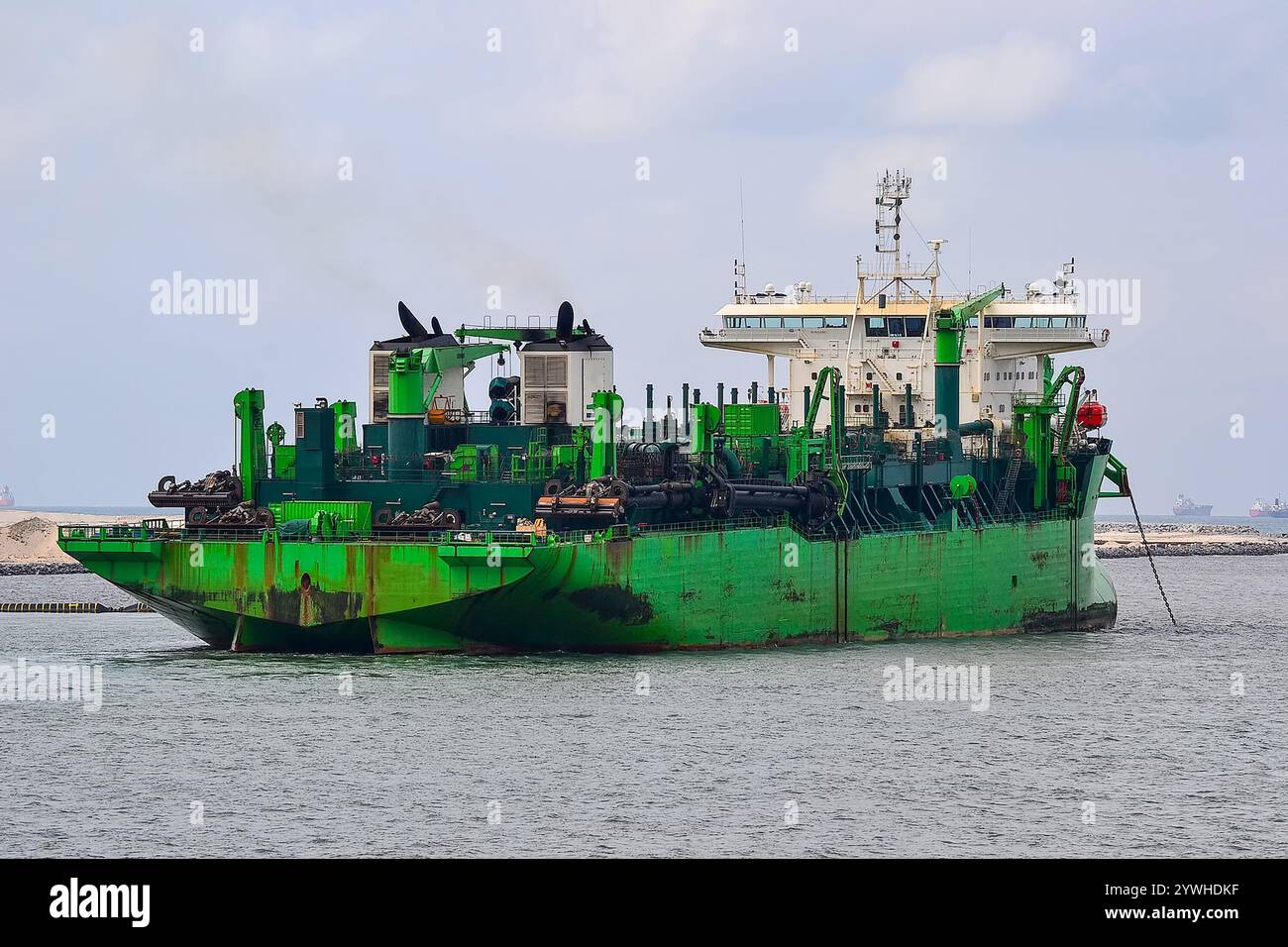 Large green trailing suction hopper dredger working near the coast ...