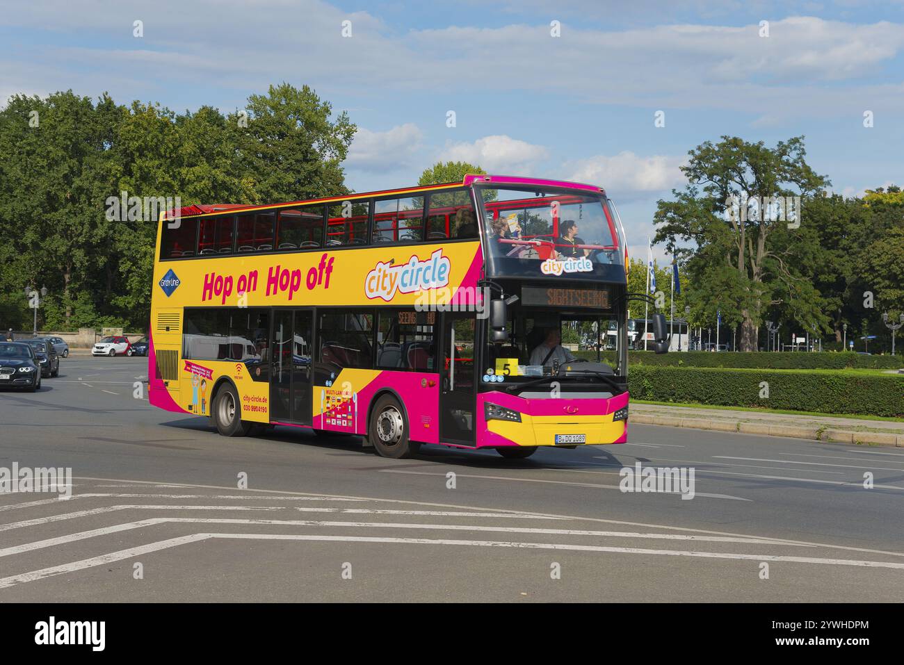 A red and yellow double-decker bus drives through the city, surrounded ...