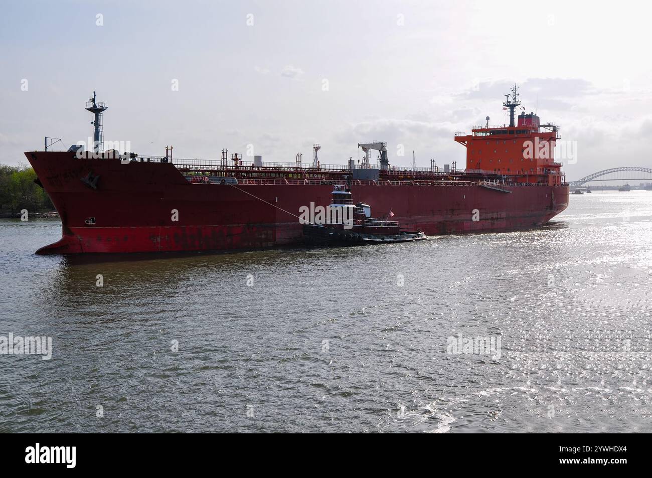 Tugboat guides a tanker through a river, showcasing maritime logistics ...