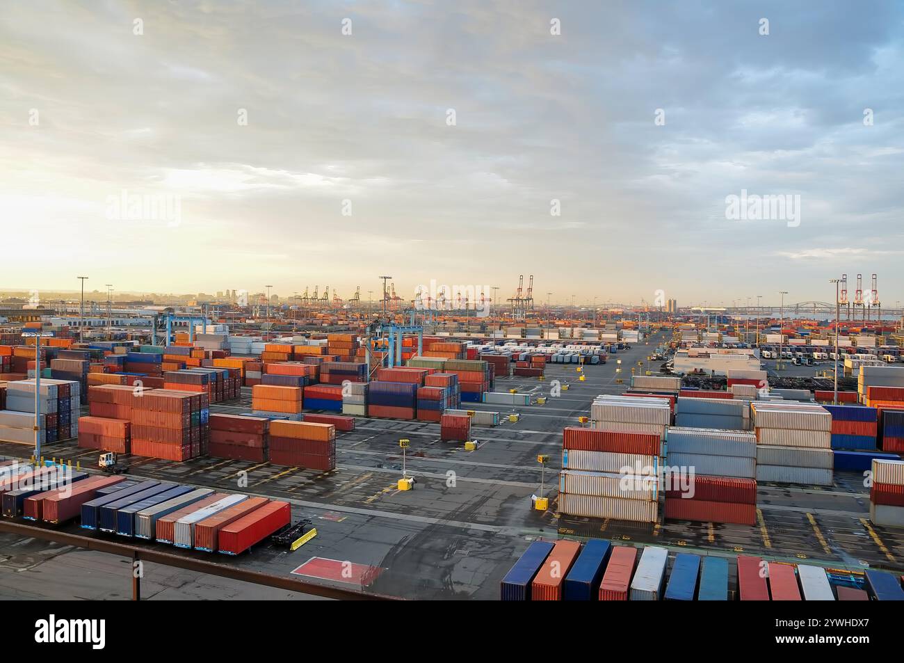 Colorful cargo containers sit in an industrial shipping port at sunset ...