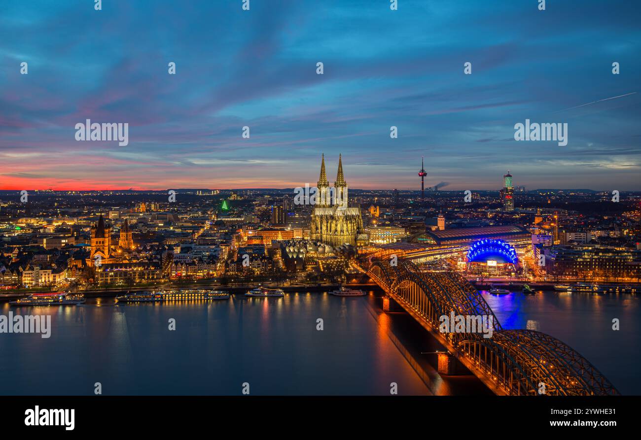 City skyline of Cologne at dusk with illuminated landmarks and river ...