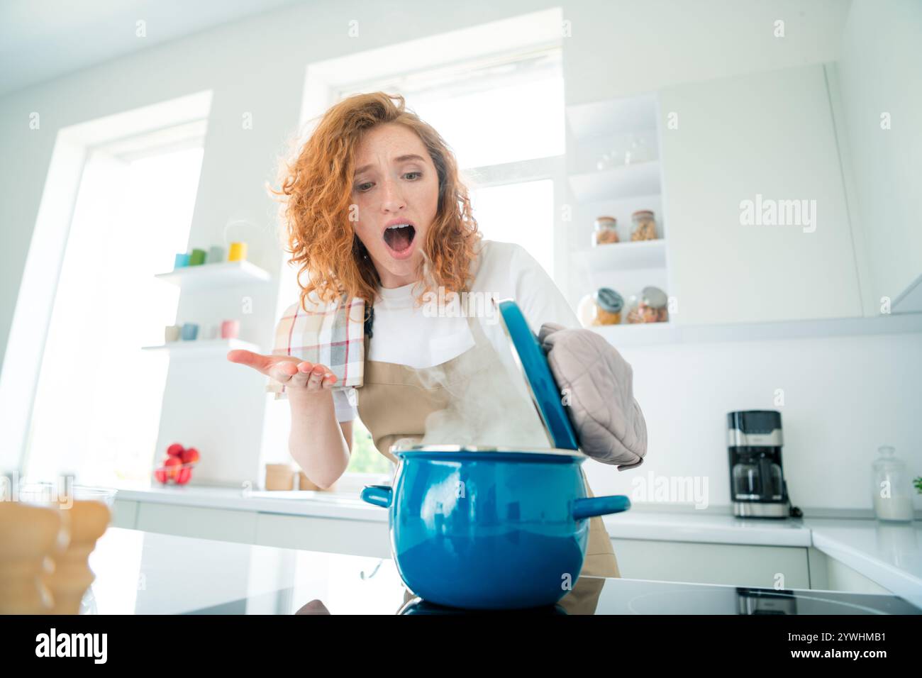 Young woman surprised while cooking in a sunny kitchen with delightful ...