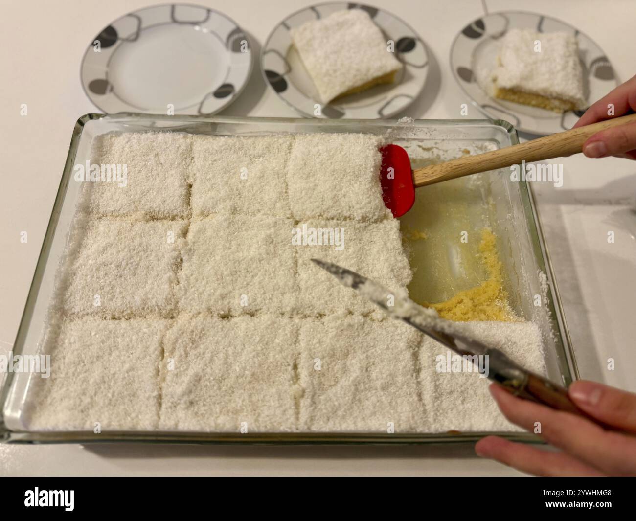 Using a spatula and knife to serve a square of coconut cake Stock Photo ...