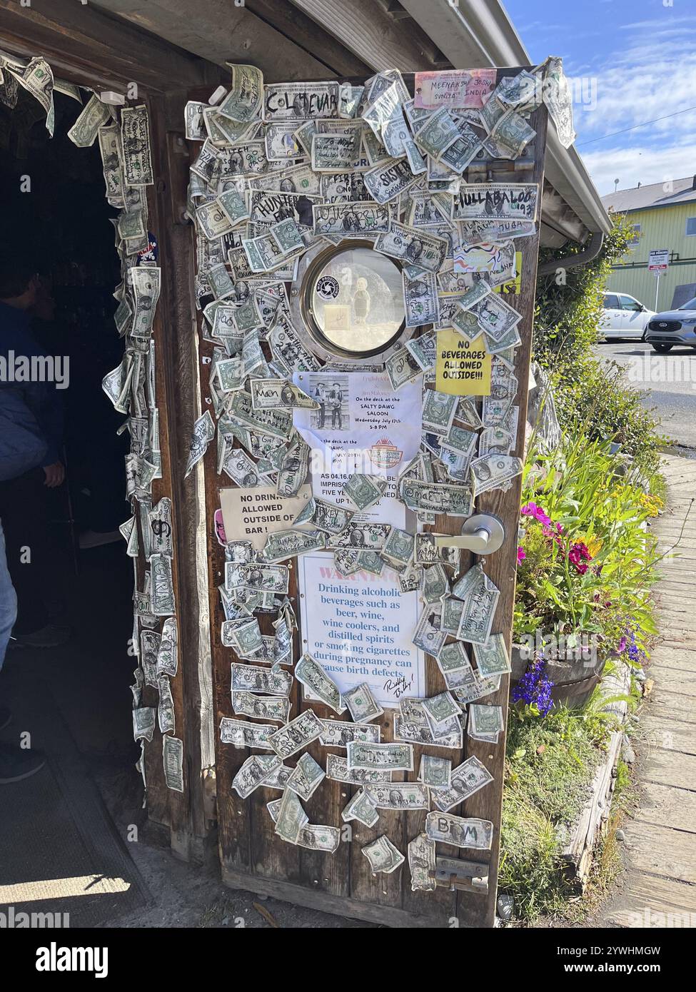Wooden door decorated with many attached banknotes and small signs ...