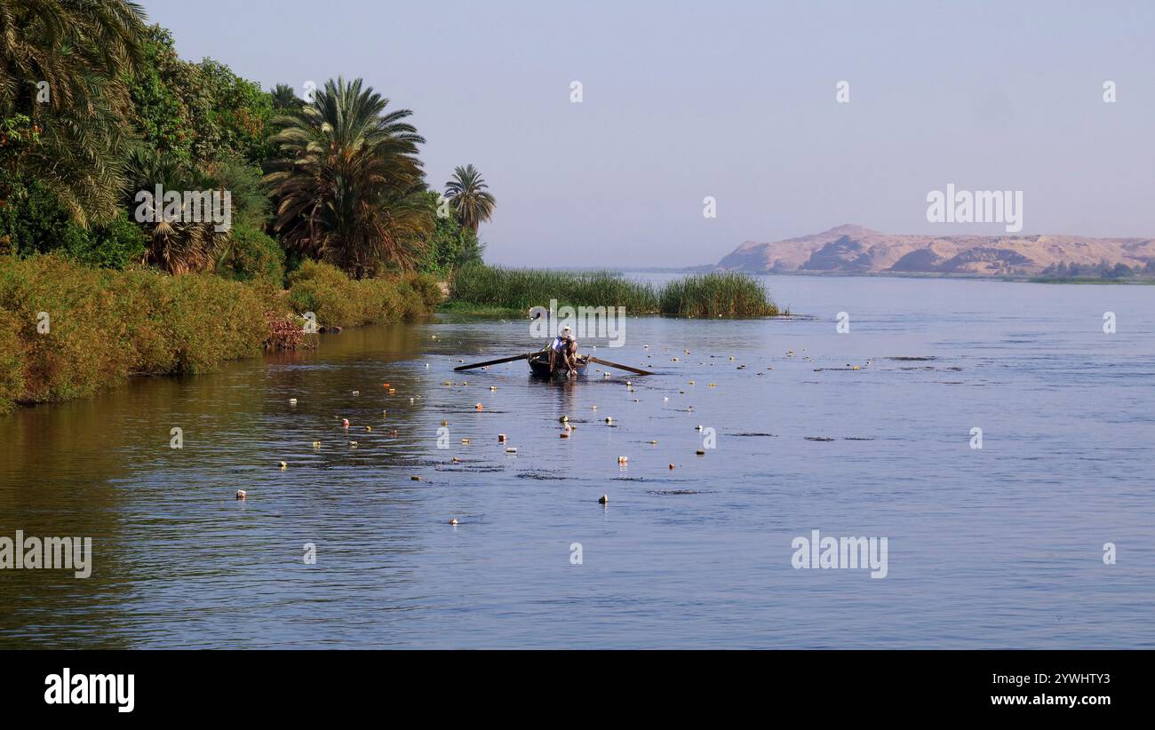 Fisherman in rowing boat on Nile River fishing by riverbank in Egypt ...