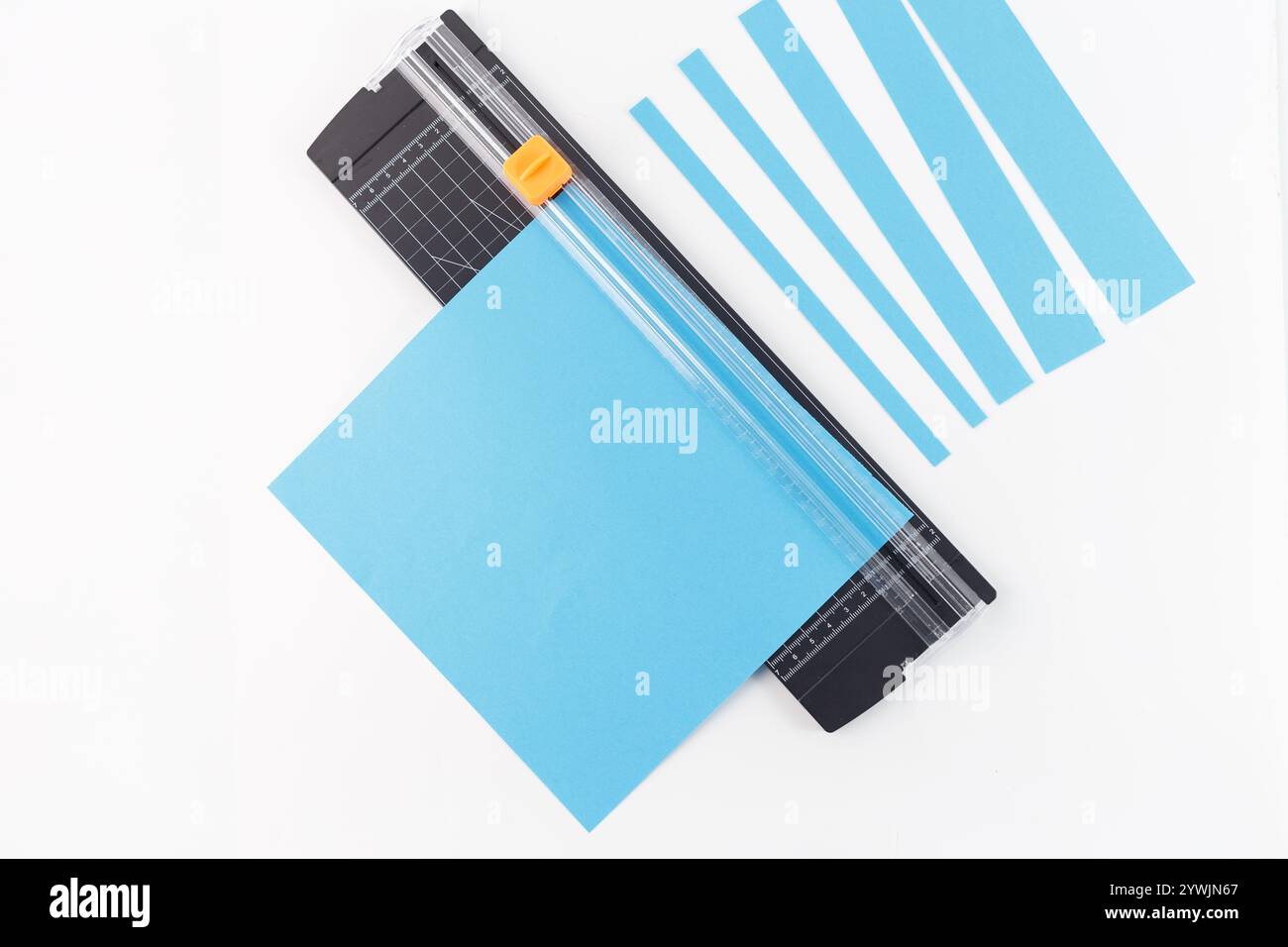 paper trimmer to cut a blue sheet of paper. top view, white background ...