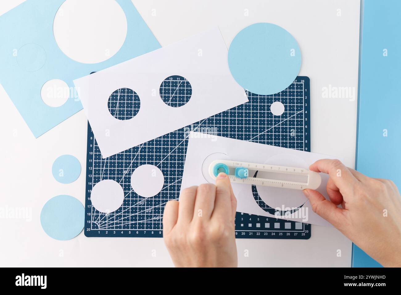 top down view hands using manual rotary cutting tool for cut out paper ...