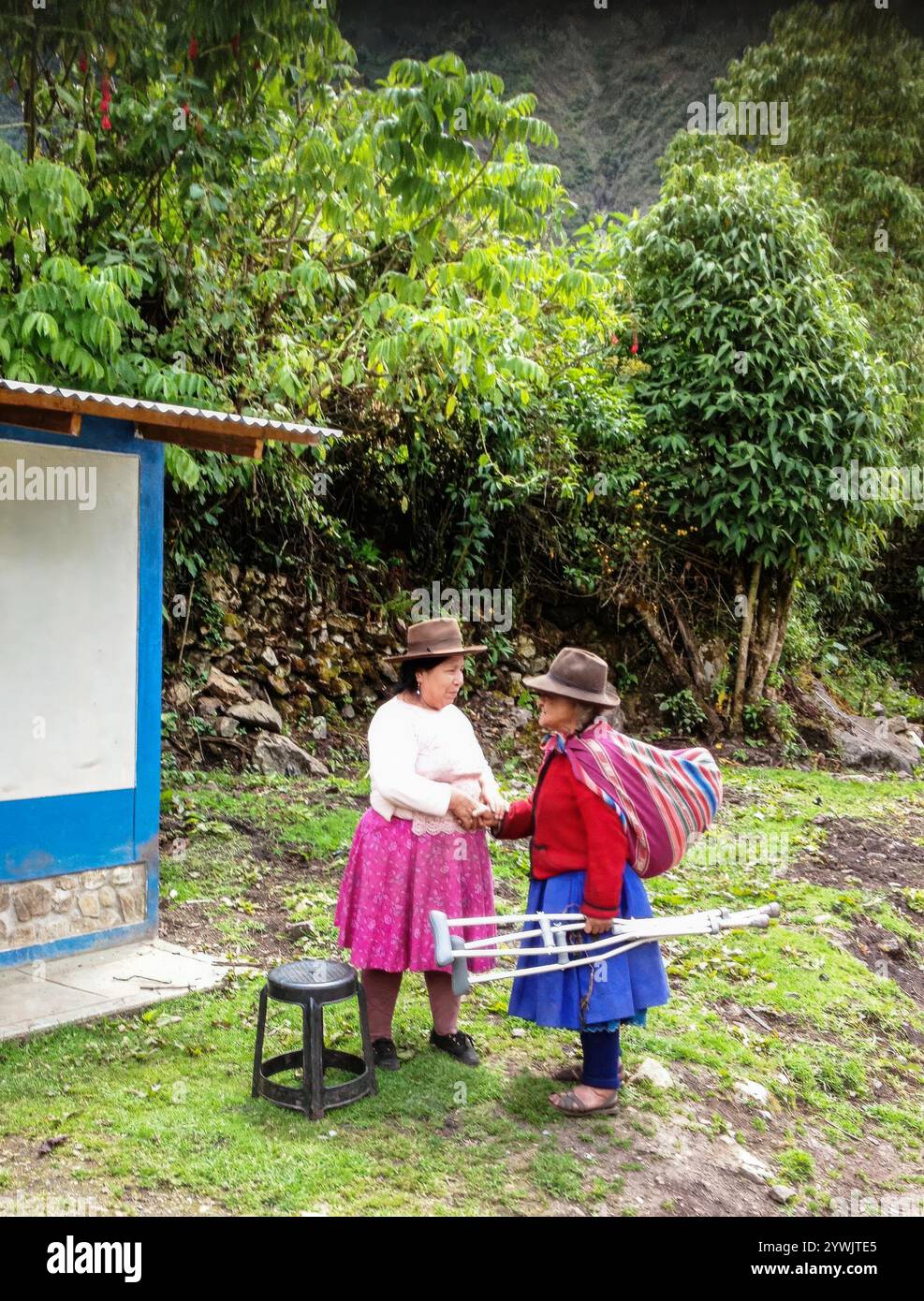 Two local women wearing traditional clothing and hats chatting, one ...