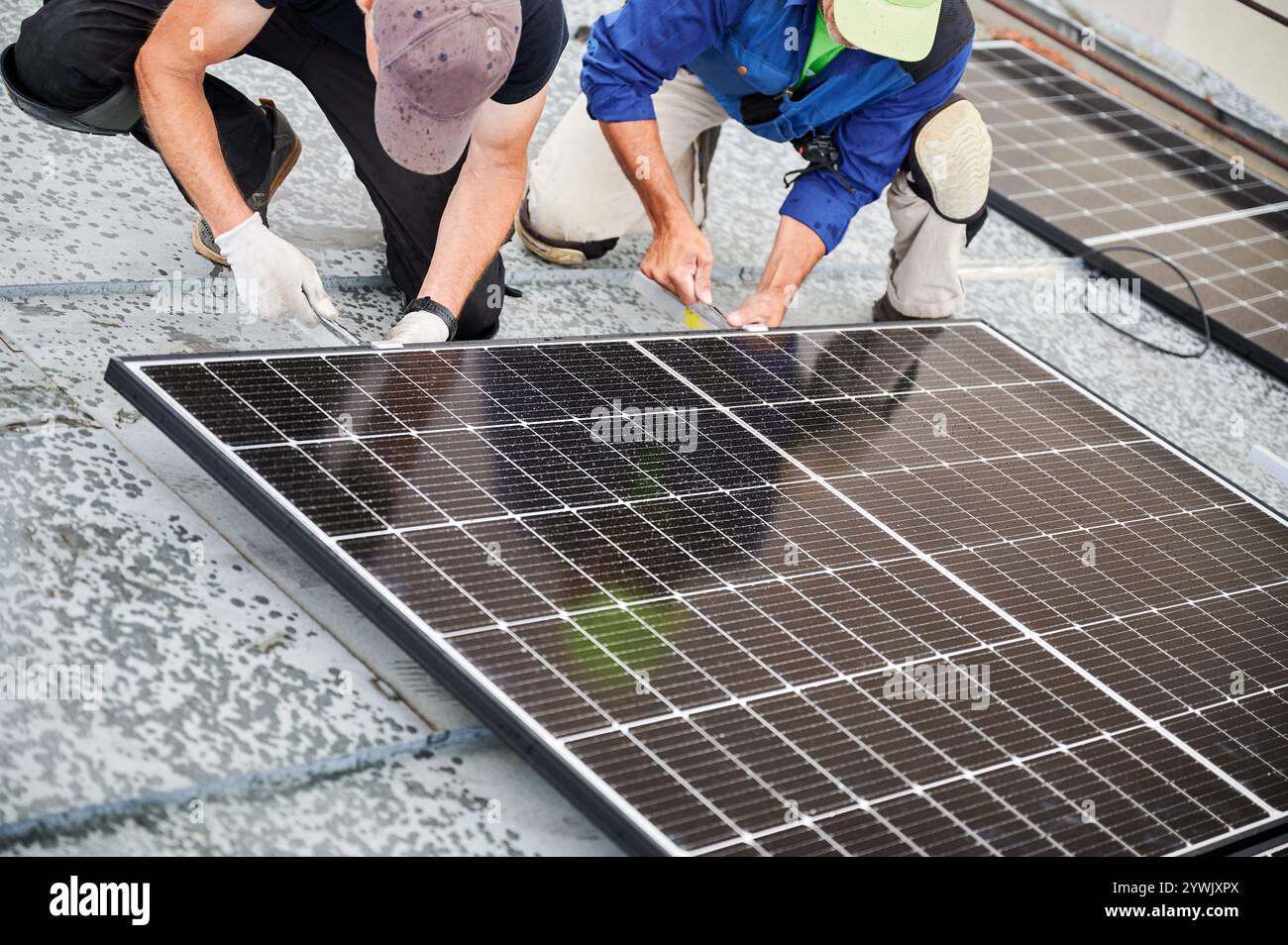 Workers building photovoltaic solar panel system on rooftop of house ...