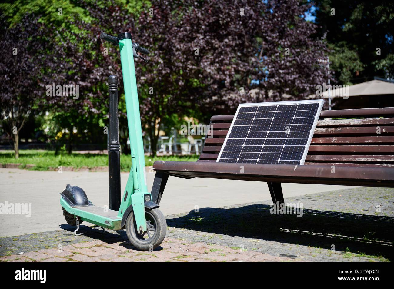 Mint-green electric scooter parked on cobblestone path next to bench in ...