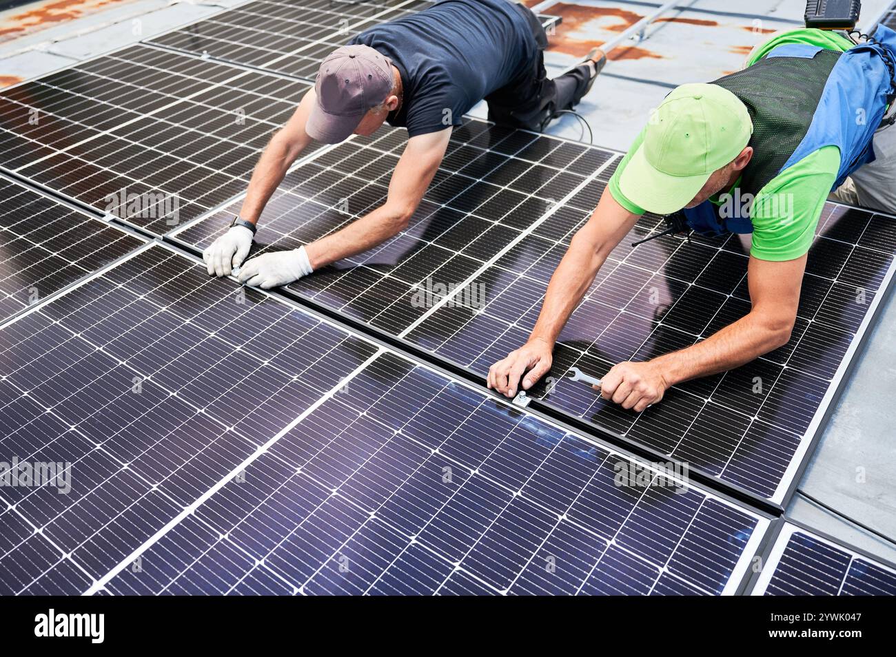 Workers building photovoltaic solar panel system on rooftop of house ...