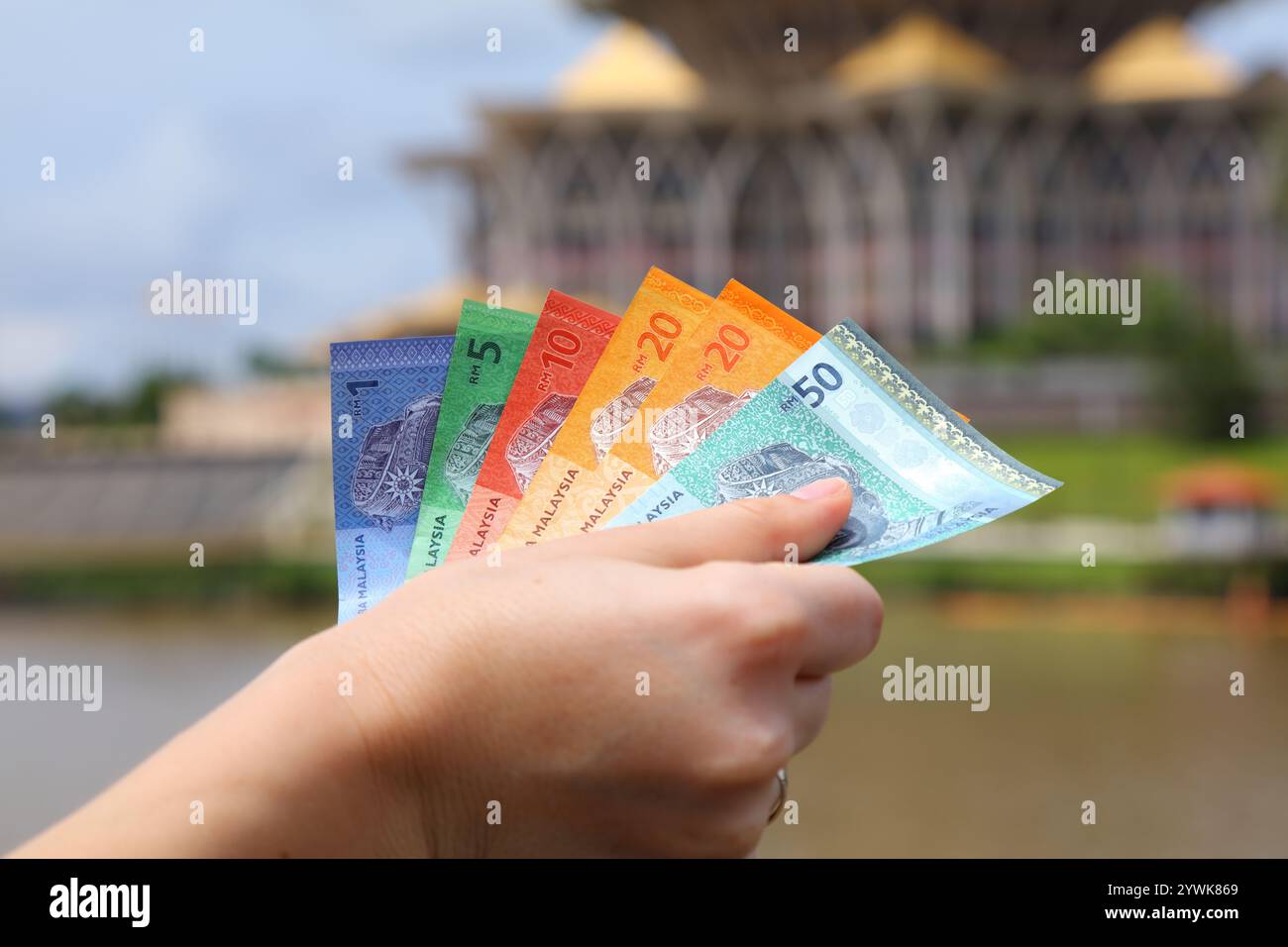 Hand holding Malaysian ringgit paper money with Kuching city skyline in ...