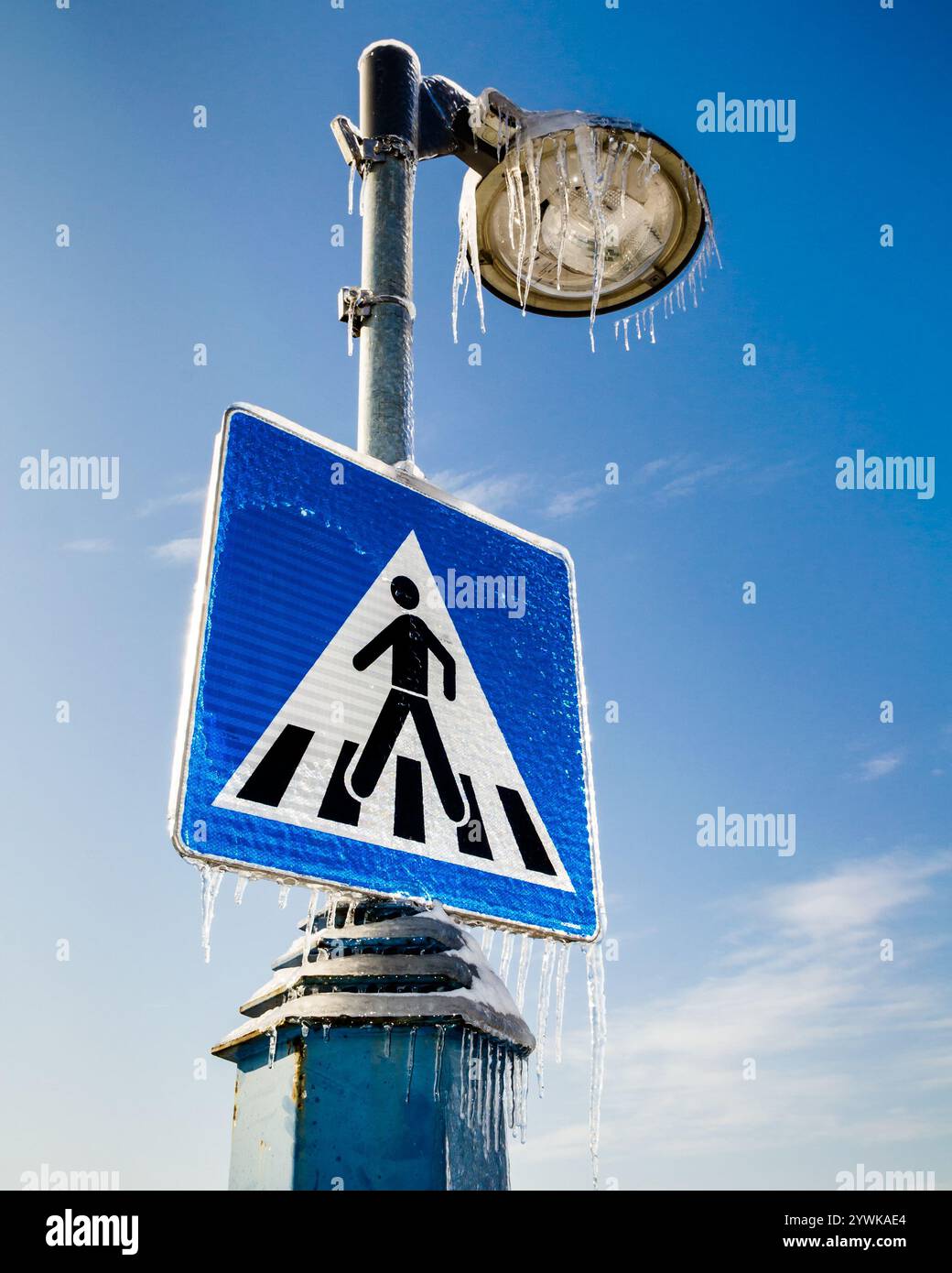 Frozen road sign for pedestrians with the street lamp above Stock Photo ...