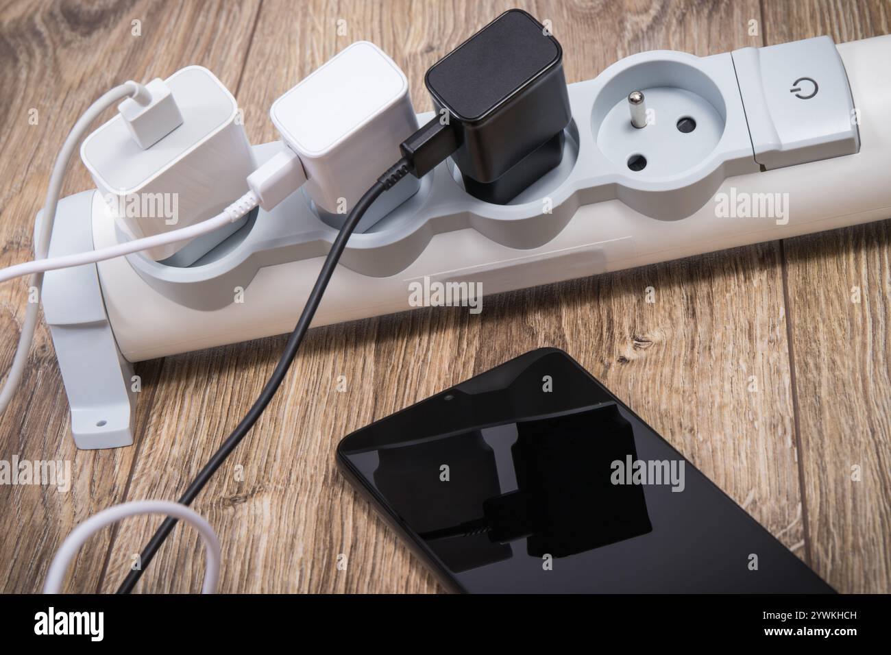 Black smartphone, mobile phone and chargers connected to electrical ...