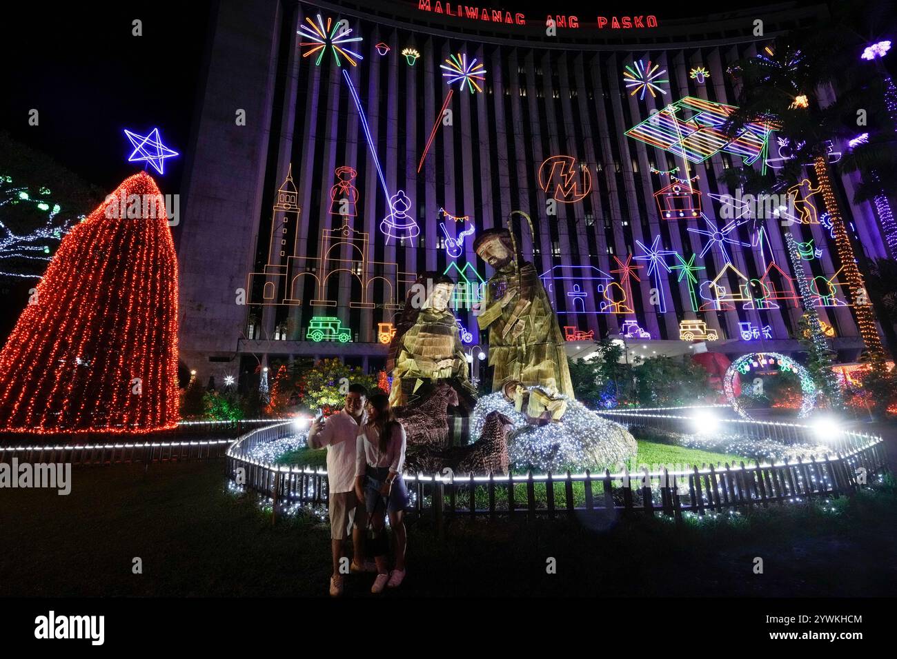 Visitors take a photo next to a Christmas display at Meralco Liwanag Park in Pasig City ...