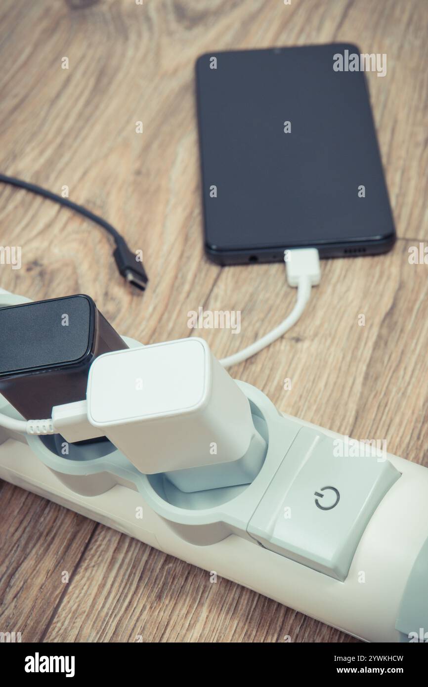 Black smartphone, mobile phone and chargers connected to electrical ...